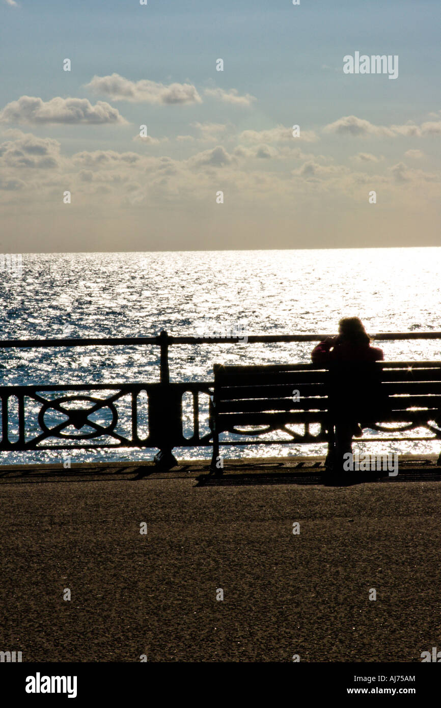 A silhouette of a person sitting on a bench on Hove seafront, Brighton ...