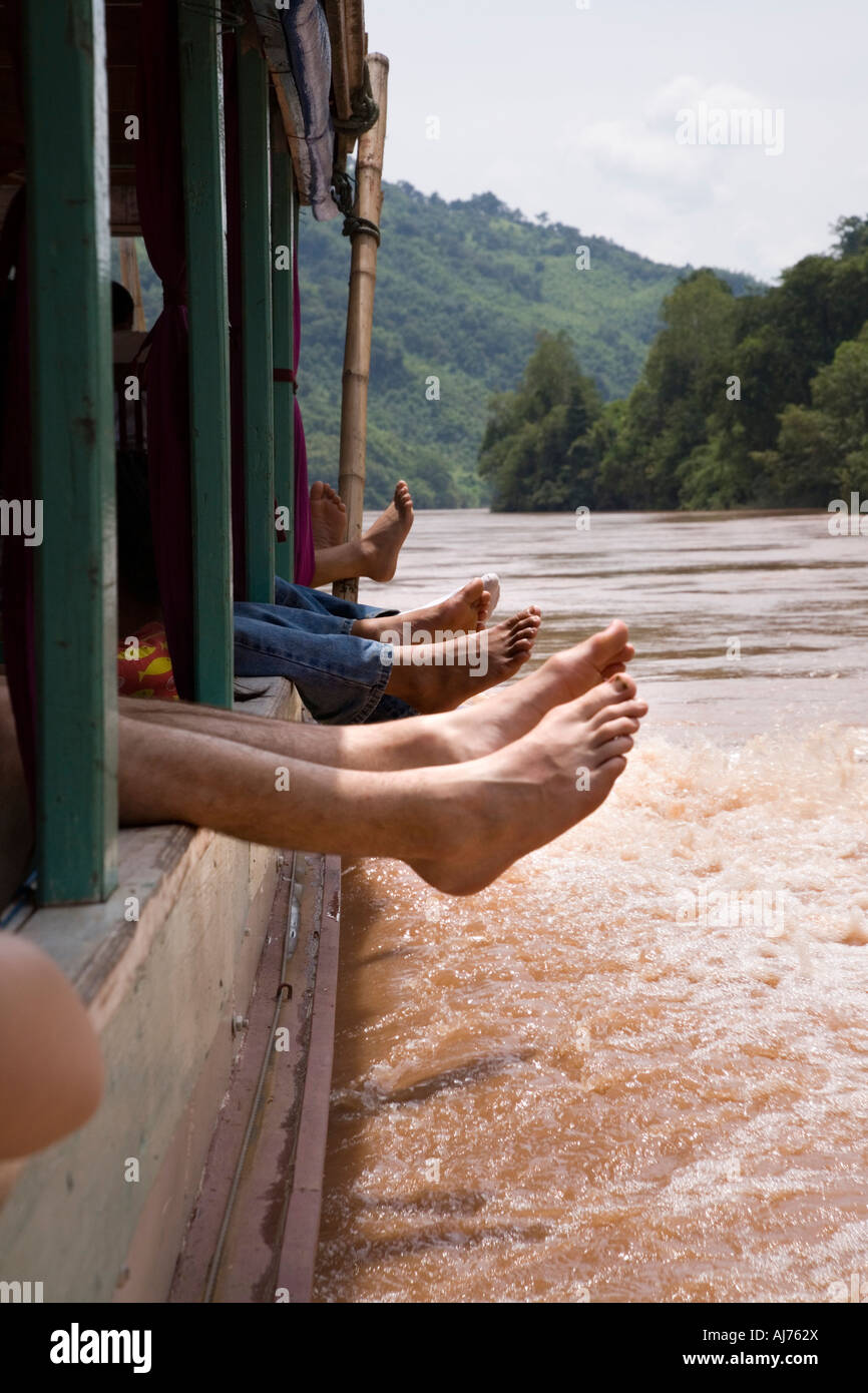 passengers hang their feet from the windows on the slow boat between ...