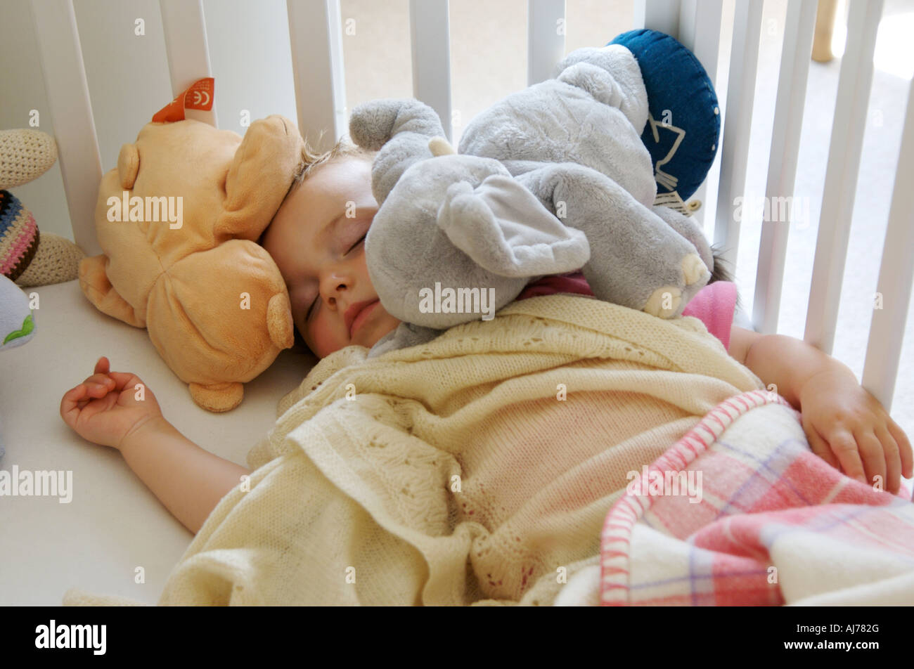 Contented baby fast asleep surrounded by teddies Stock Photo - Alamy