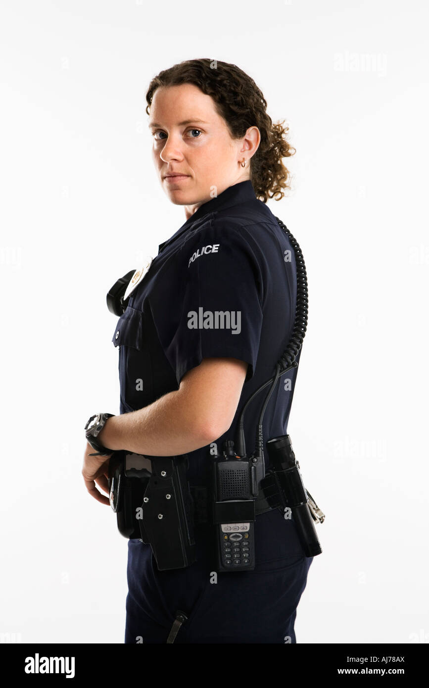 Portrait of mid adult Caucasian policewoman standing with hand on gun ...