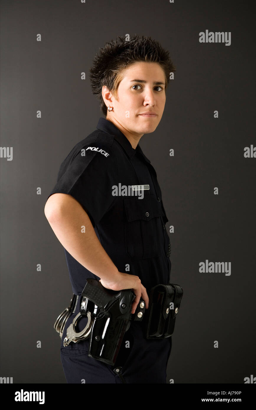 Portrait of mid adult Caucasian policewoman standing with hand on gun ...