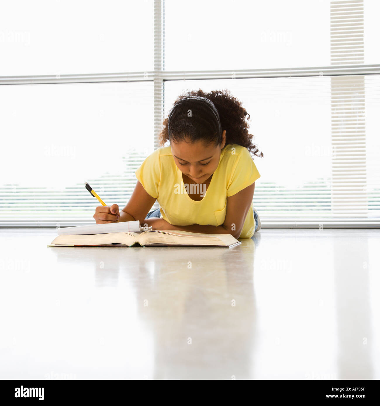 African American girl lying on floor doing homework Stock Photo - Alamy