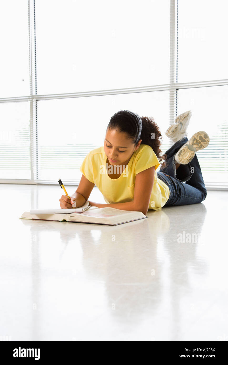 African American girl lying on floor doing schoolwork Stock Photo - Alamy