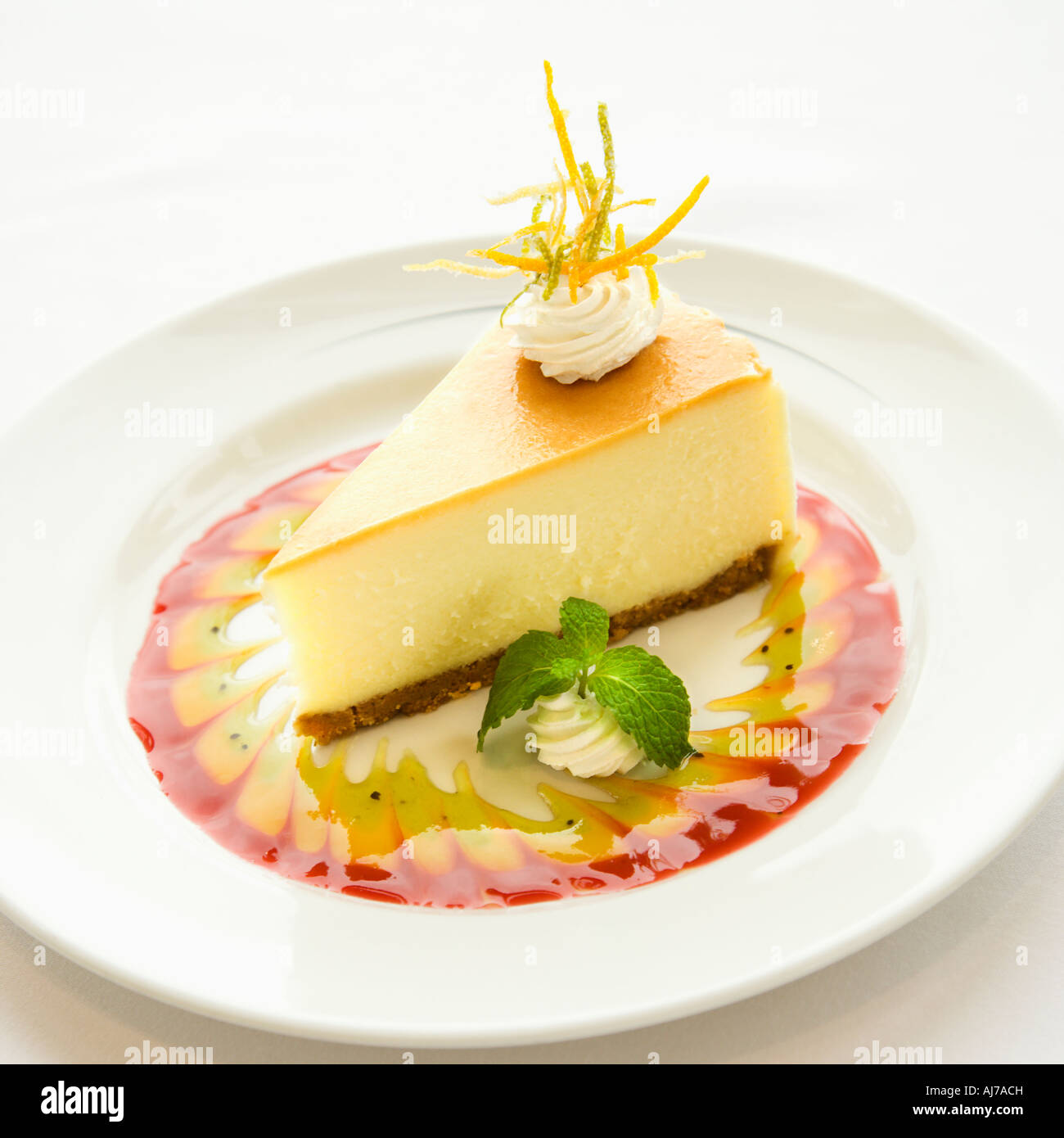 Gourmet slice of cheesecake garnished with zest and sauce and mint ...