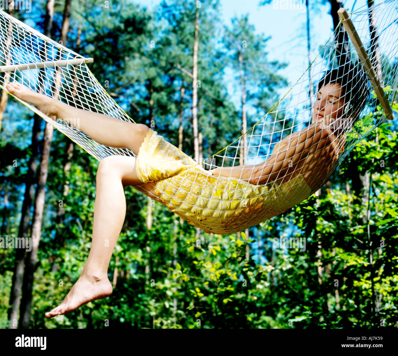 Woman in earphones lying in a hammock and listening to the music Stock ...