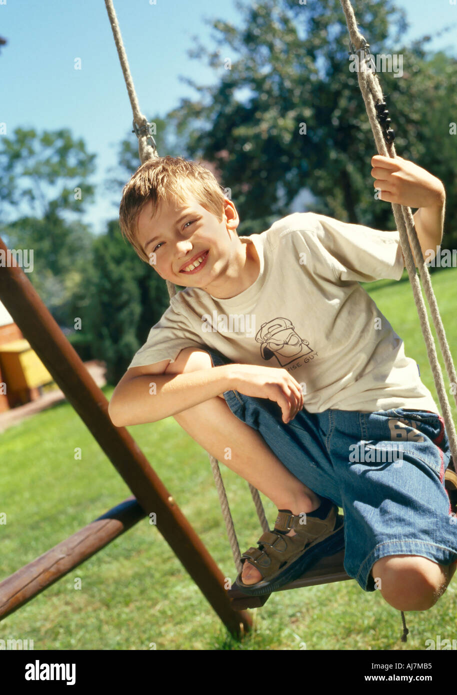 outdoor summer day park playground child boy blonde sit stand swing ...