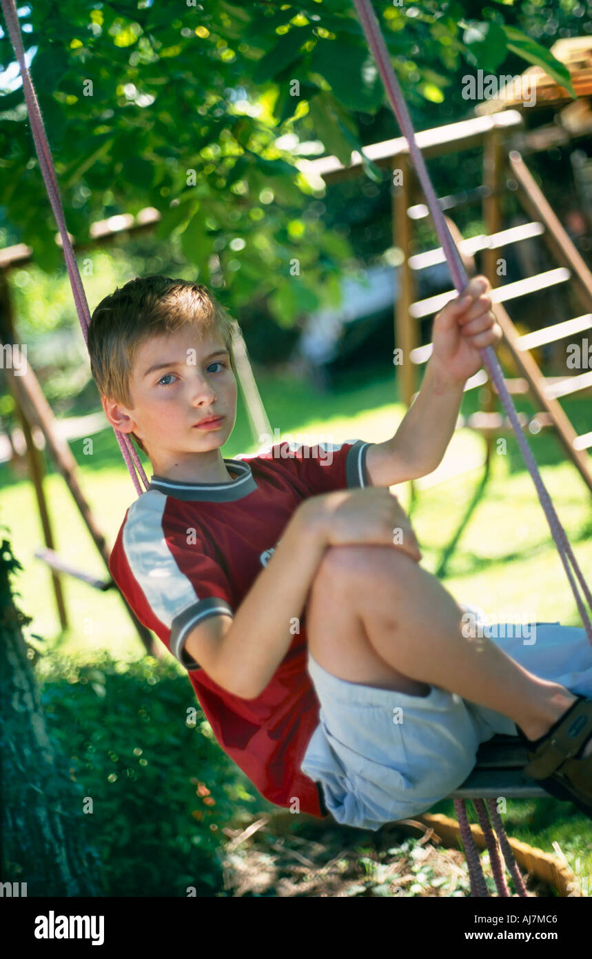 outdoor summer day park playground child boy blonde sit swing teeter ...