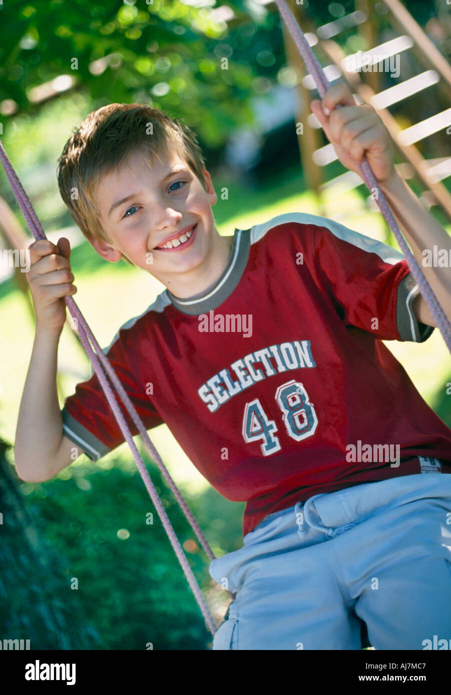 outdoor summer day park playground child boy blonde sit swing teeter ...