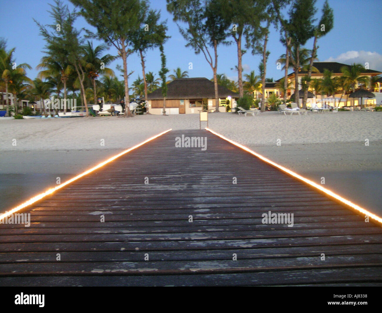 Lights on wooden boardwalk at dusk by sandy beach, Mauritius Stock ...