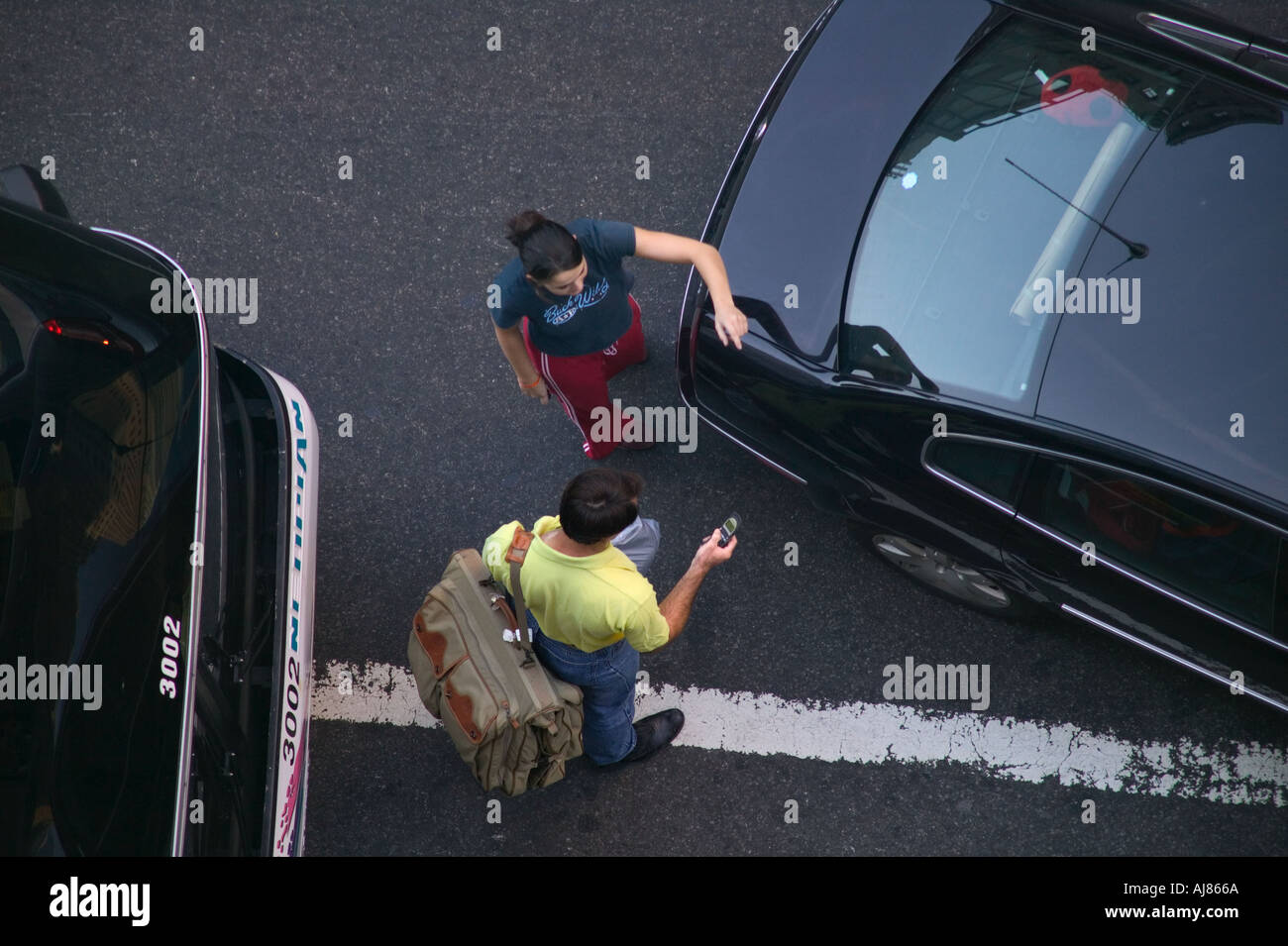 Overhead view of man with luggage and cell phone and a woman pointing ...