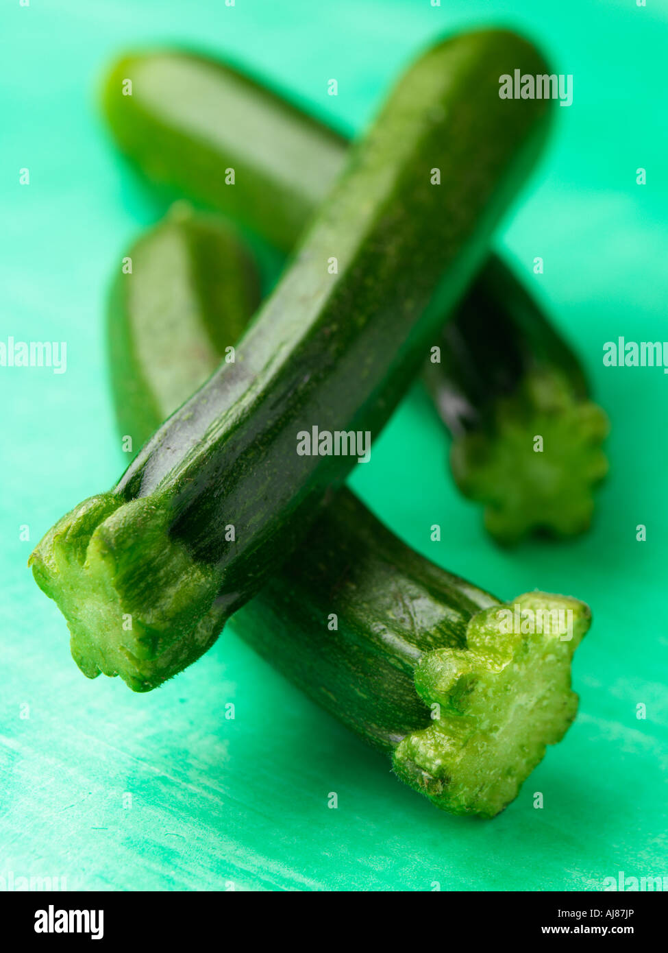 Three baby cougettes on a green background Stock Photo - Alamy