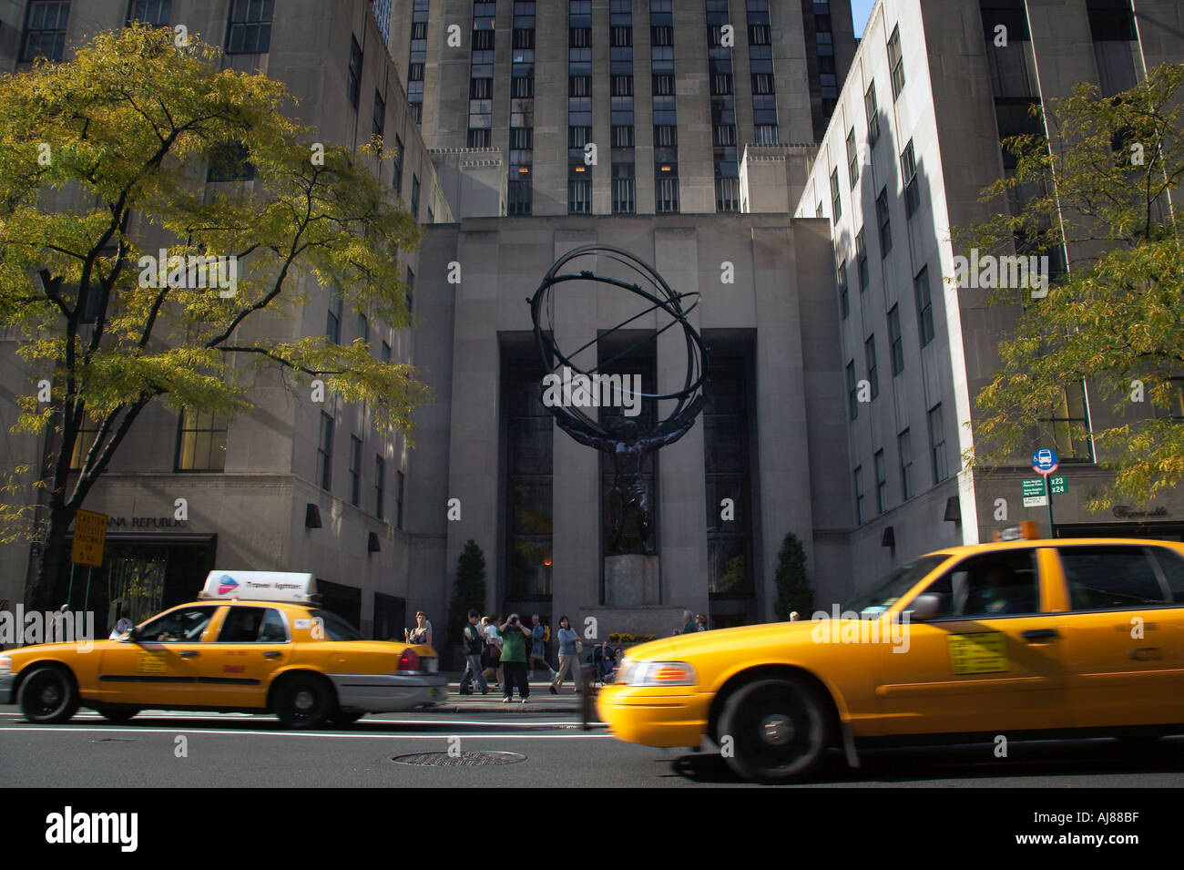 Taxis and pedestrians on Fifth Avenue with sculpture of Atlas holding ...