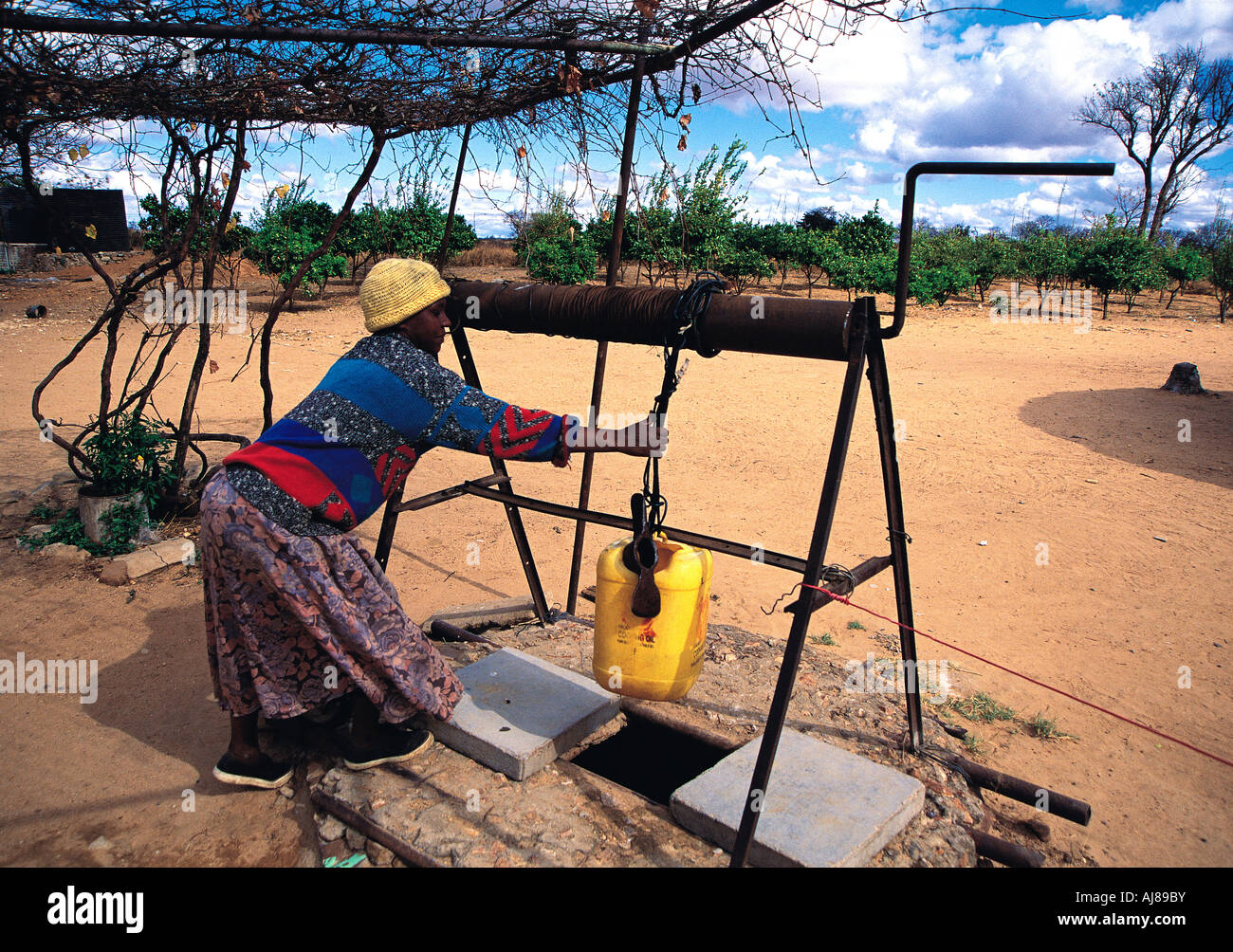 A black African woman with a yellow plastic water container at a ...