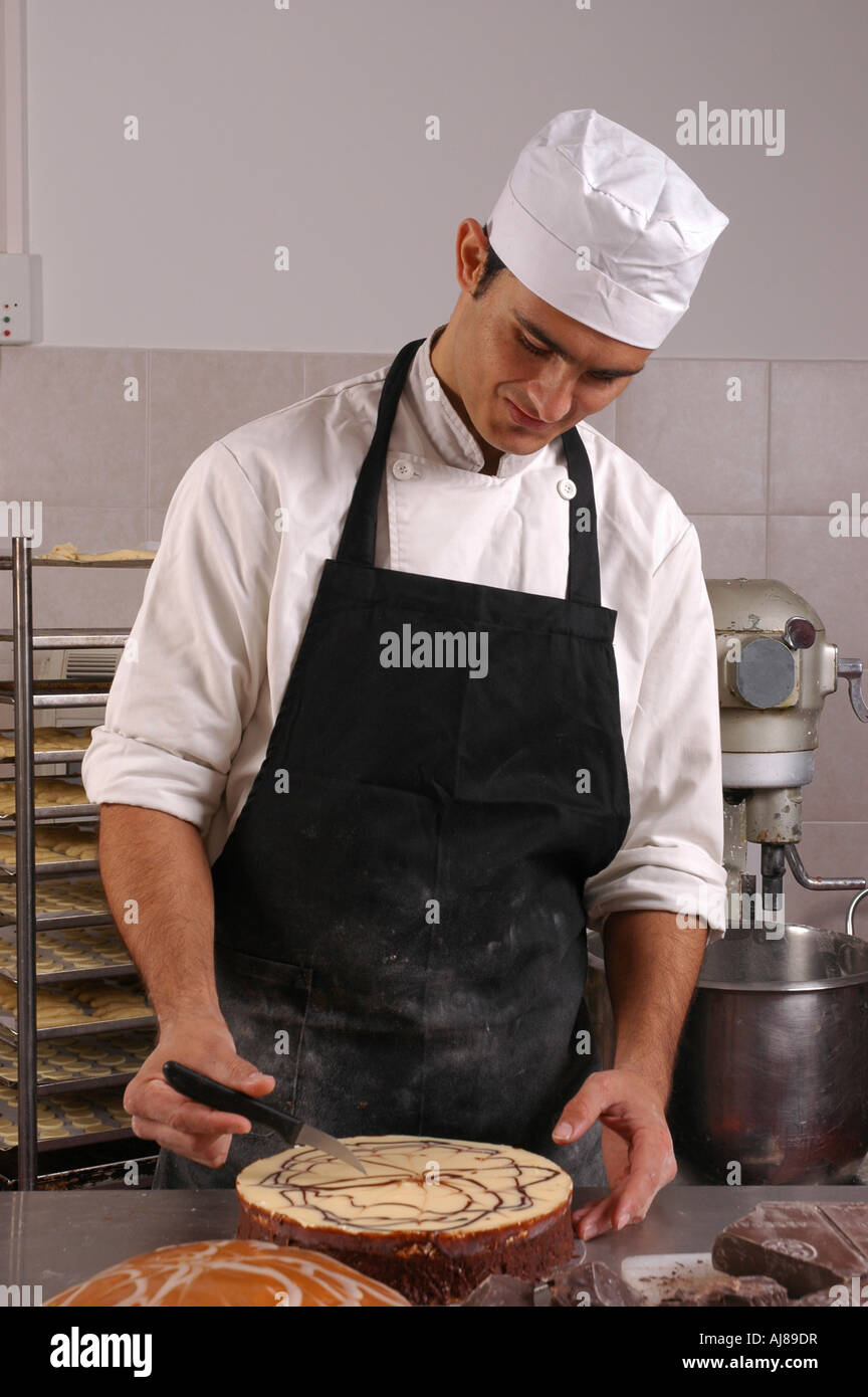 Male baker in his bakery decorating the cake after baking Stock Photo ...