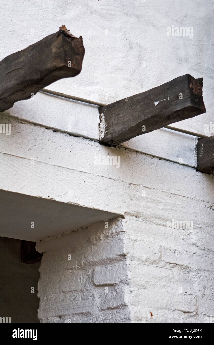 Two wooden rail road beams protruding out of a whitewashed building ...