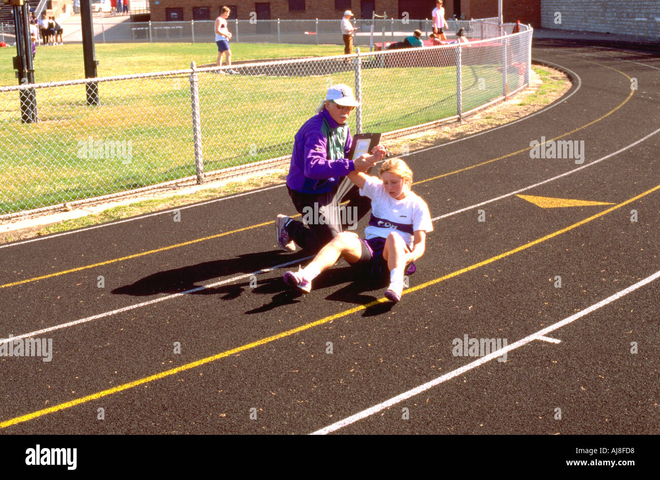 Coach and runner ages 51 and 16 helping her up from a fall. St Paul ...