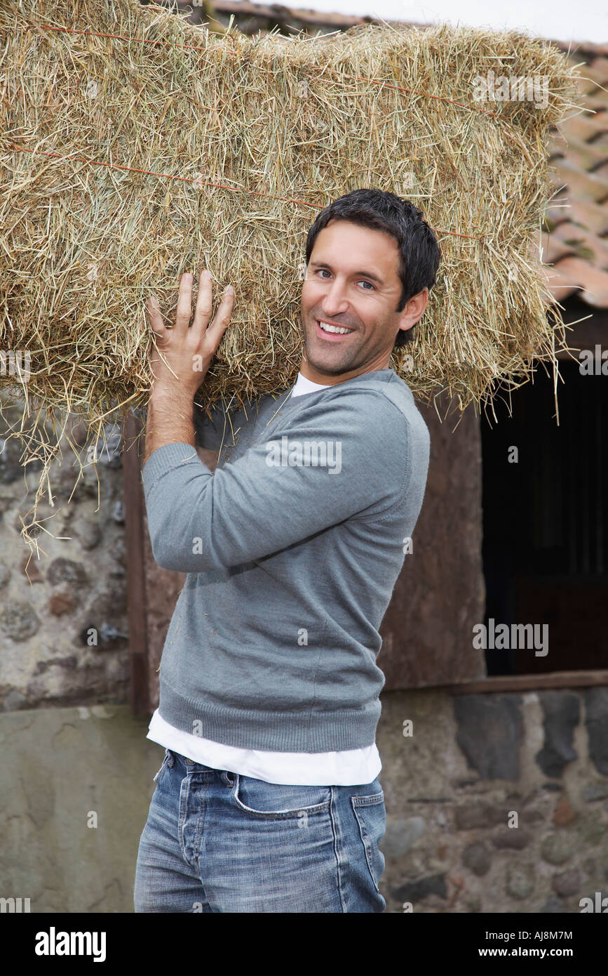 Man carrying hay on shoulders, outdoors, portrait Stock Photo - Alamy