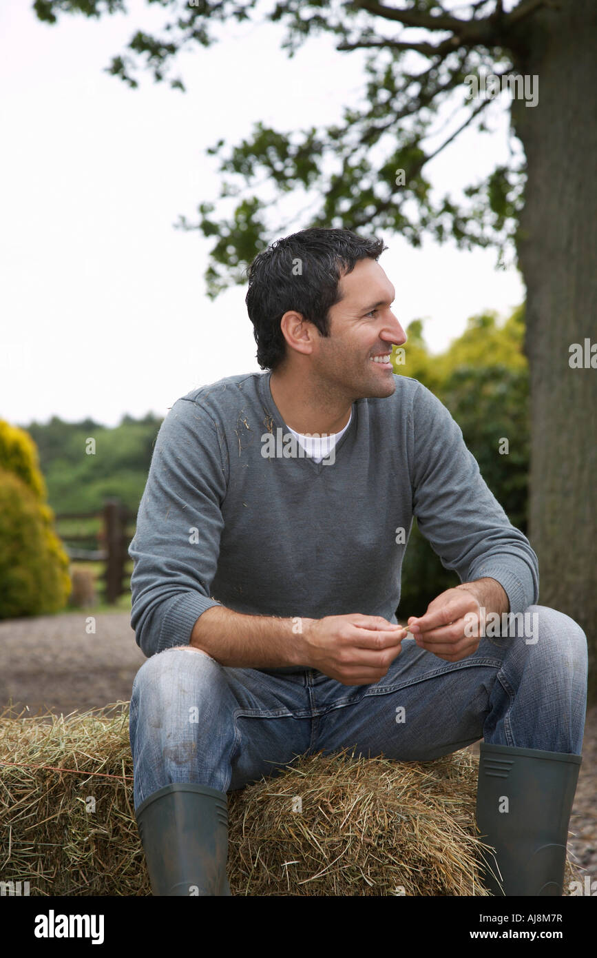Man sitting on hay bale in countryside Stock Photo - Alamy