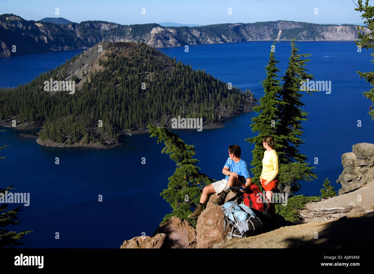 Hikers along cliff trail near lake Stock Photo - Alamy