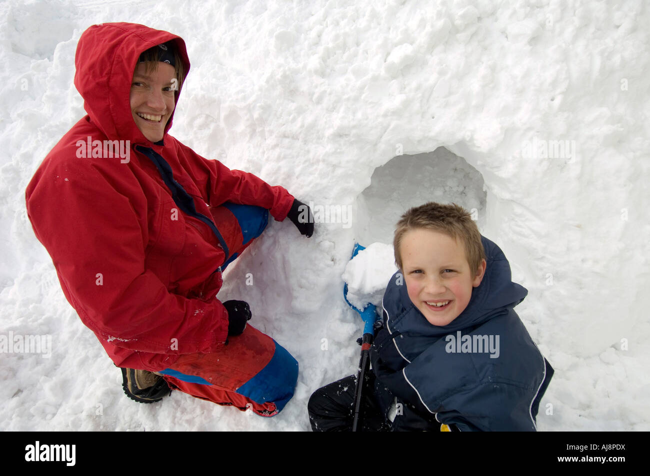 Mother and son dig a snow cave Stock Photo - Alamy