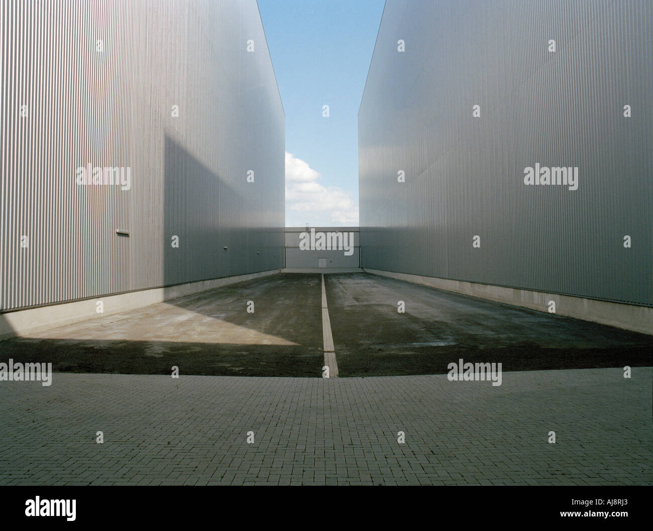 Road between warehouse buildings leading to closed gate Stock Photo - Alamy