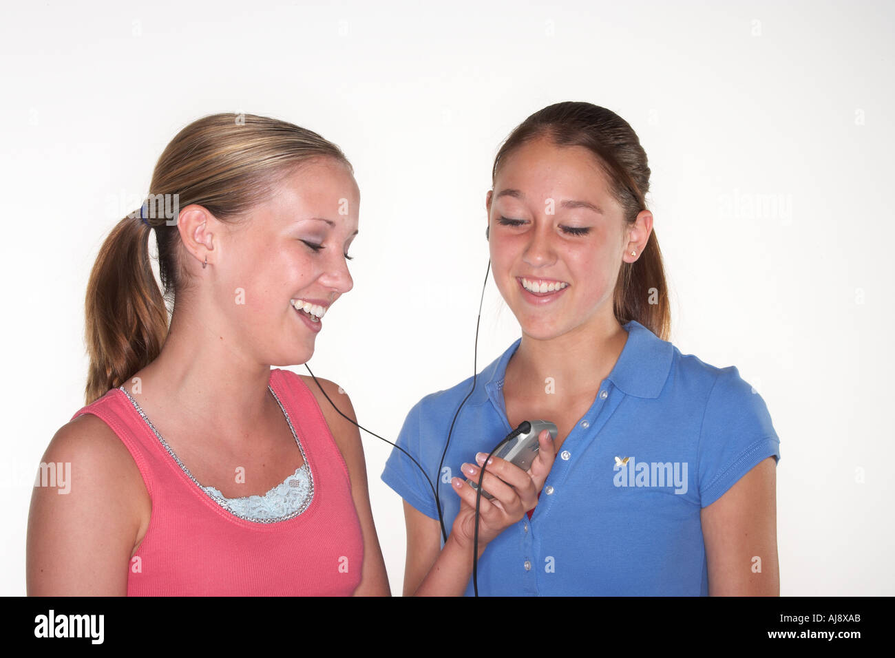 Two girls with an MP3 player listening to music Stock Photo - Alamy