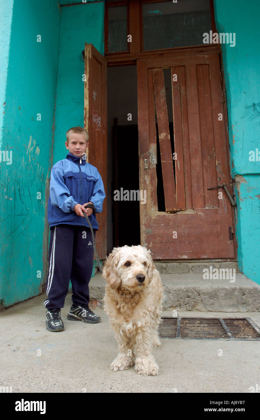 Boy with dog outside old concrete apartment building in Nogliki ...
