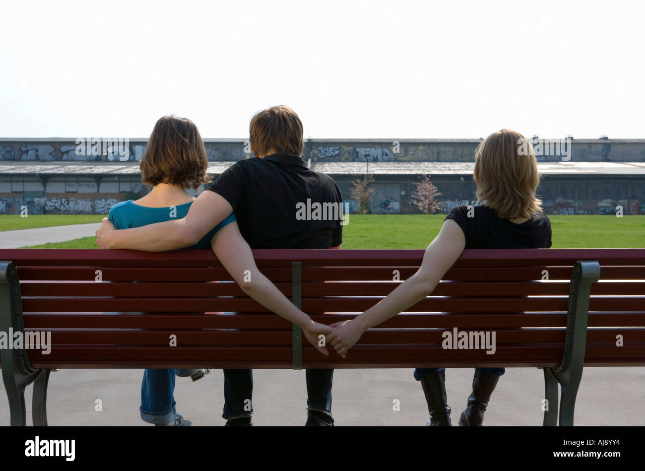 Young adults sitting on park bench Stock Photo - Alamy