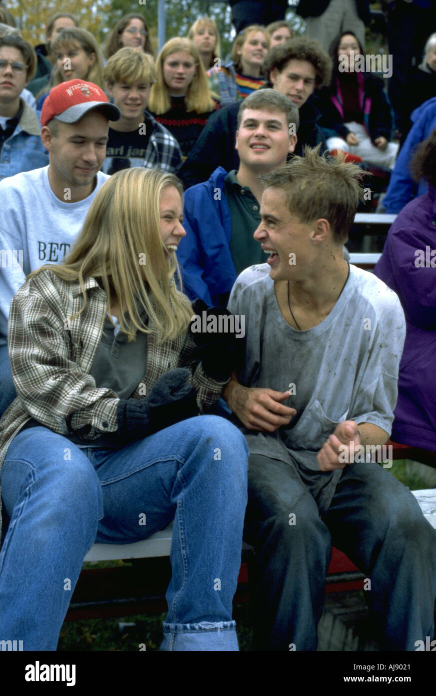 mud sliding teen with friend age 16 at wet high school football game ...