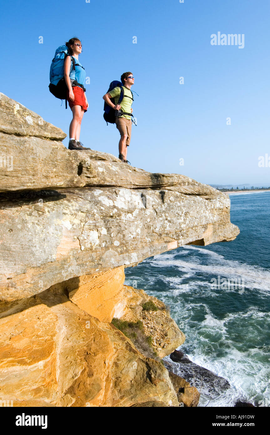 Hikers on edge of rocky ocean cliff Stock Photo - Alamy