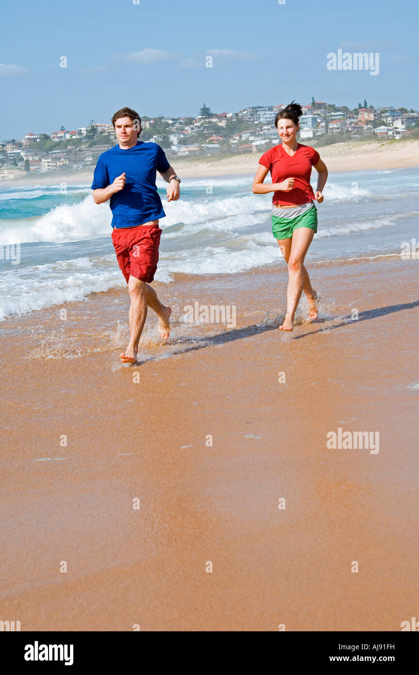 Runner in along beach in ocean surf Stock Photo - Alamy