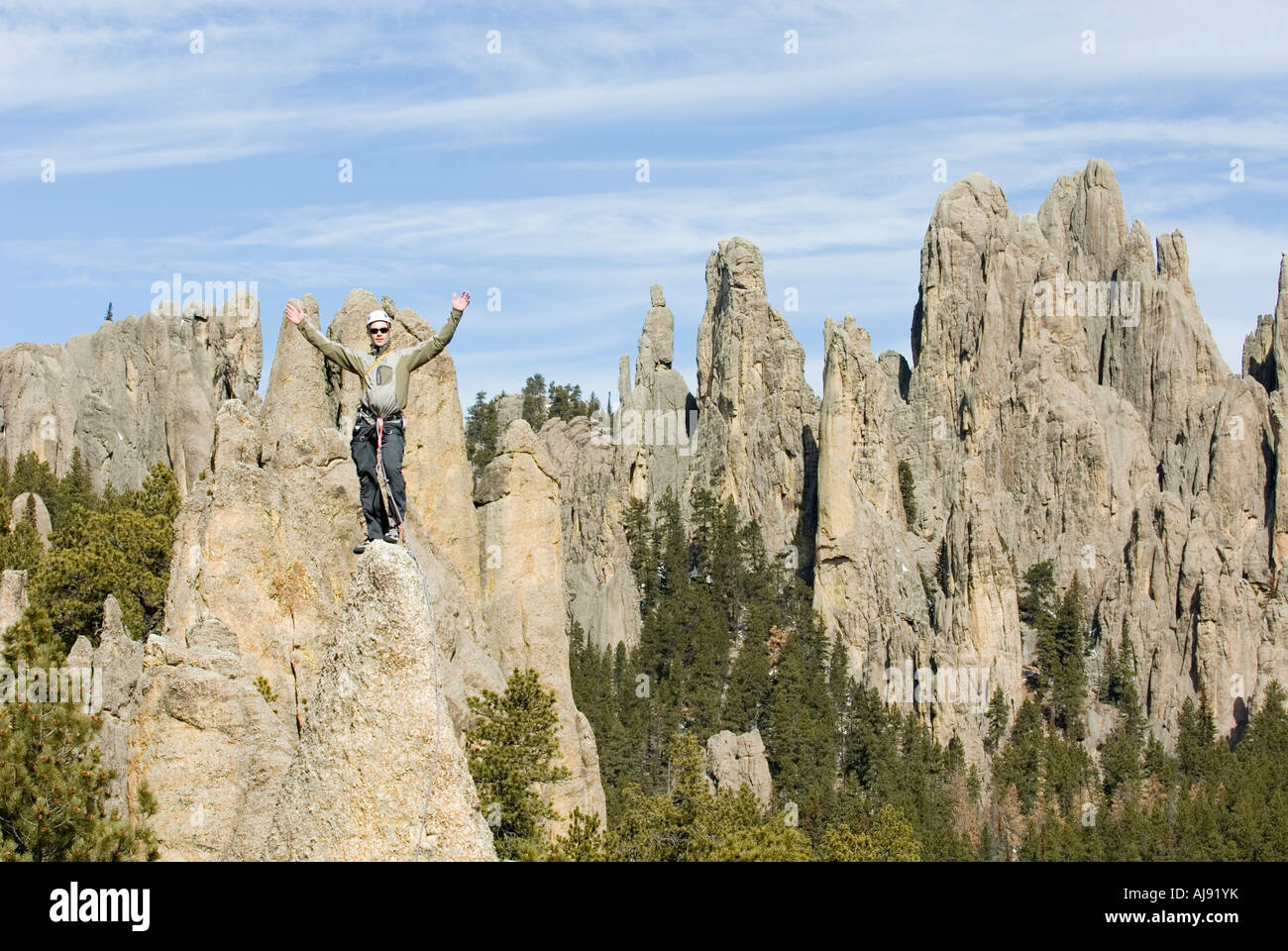 Man on rock spire with raised arms Stock Photo - Alamy