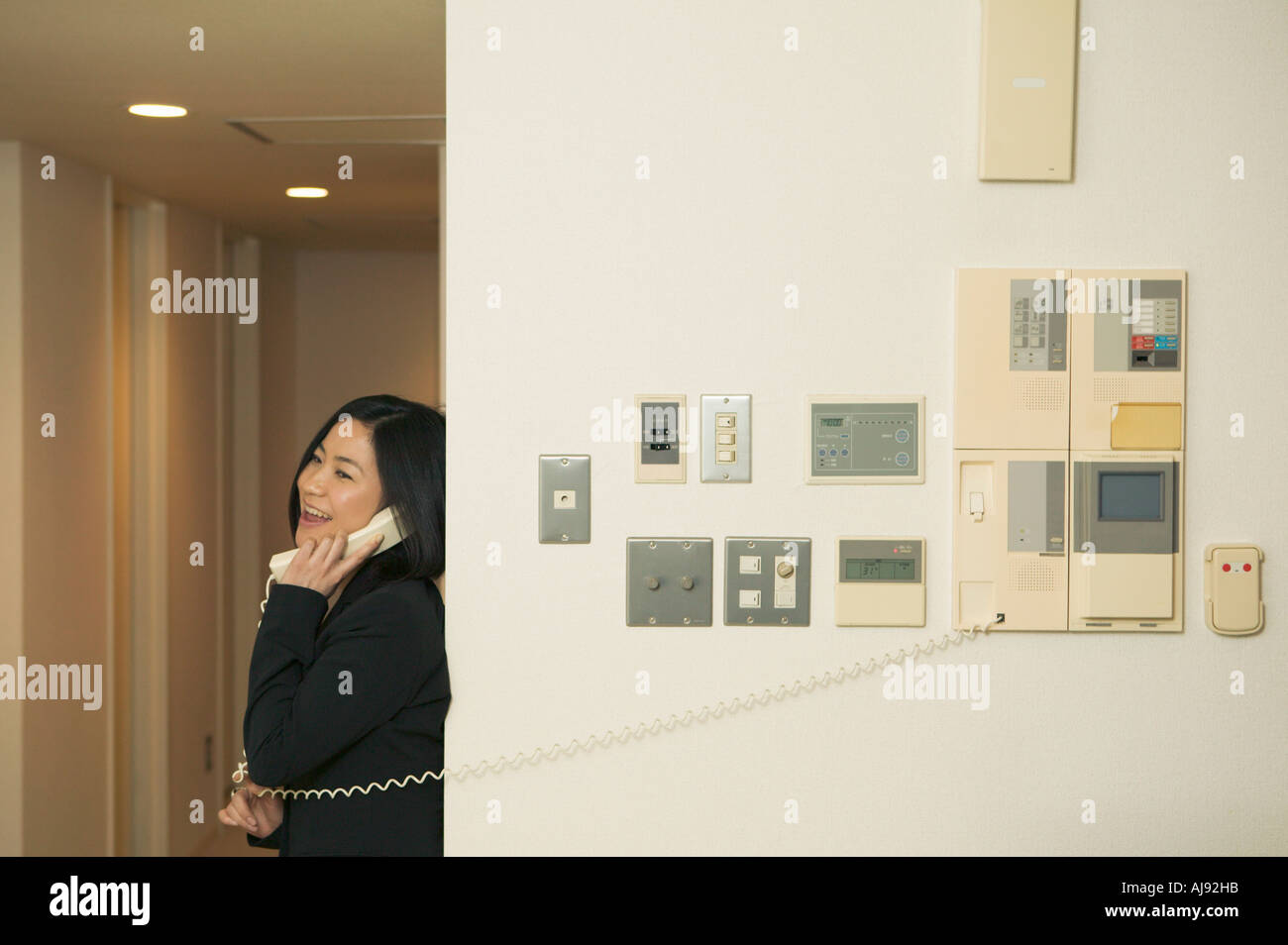 Woman standing around corner using intercom phone Stock Photo - Alamy