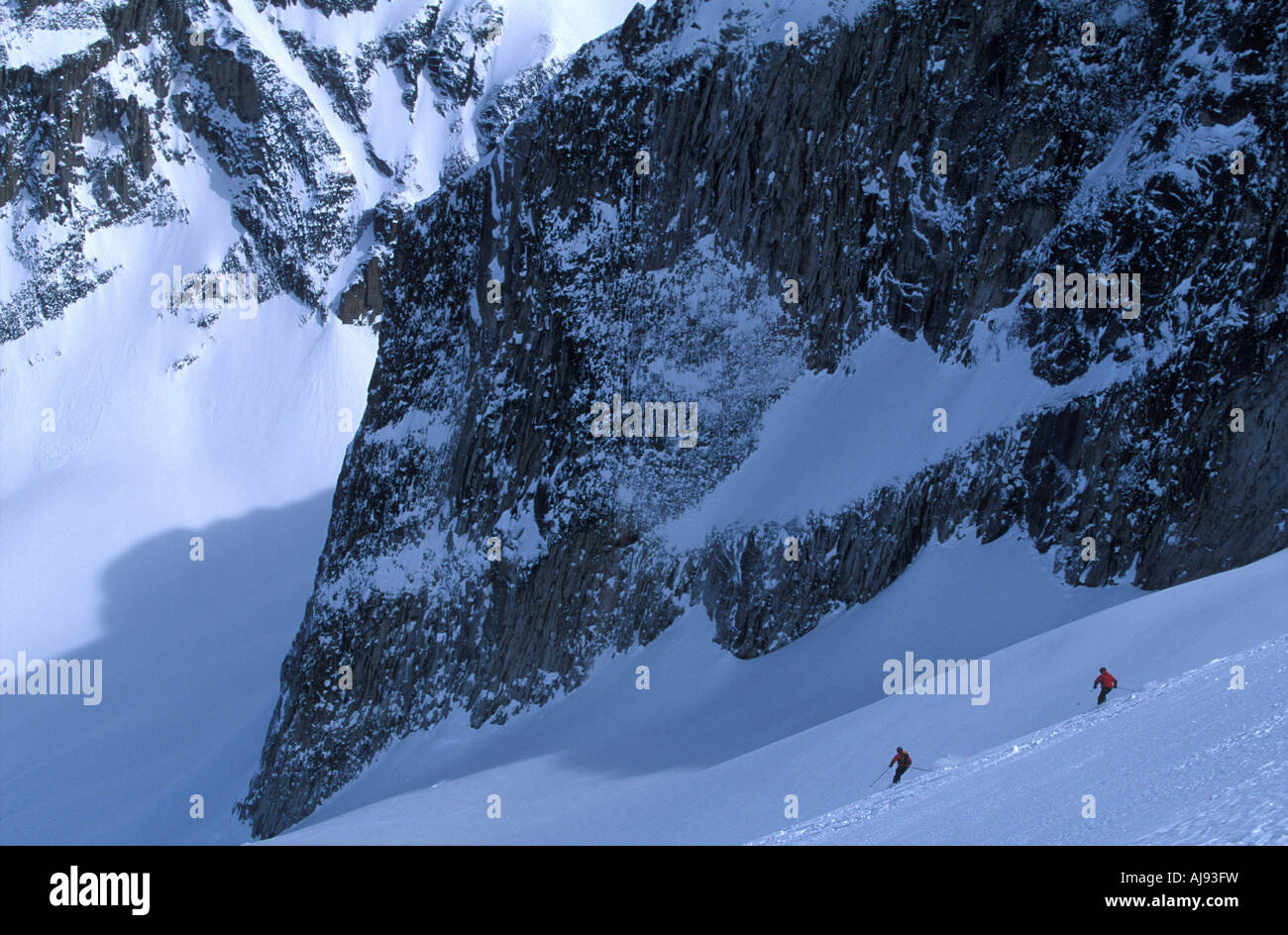 Powder skiers below cliff Stock Photo - Alamy