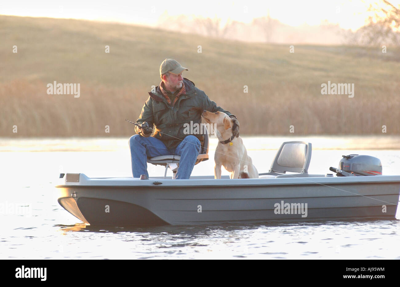 Man and dog fishing from small boat Stock Photo - Alamy