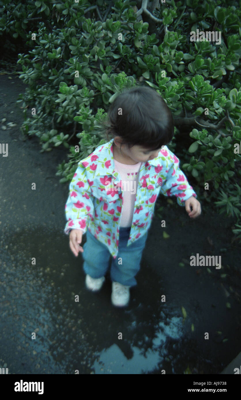 Child playing in rain stomping in a water puddle Stock Photo - Alamy