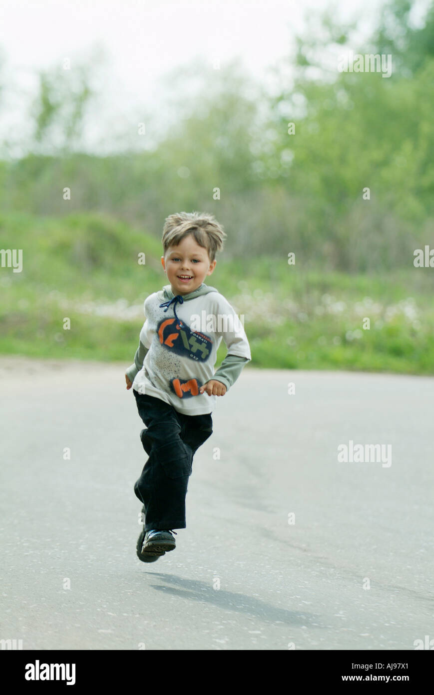 Young boy running down a road Stock Photo - Alamy