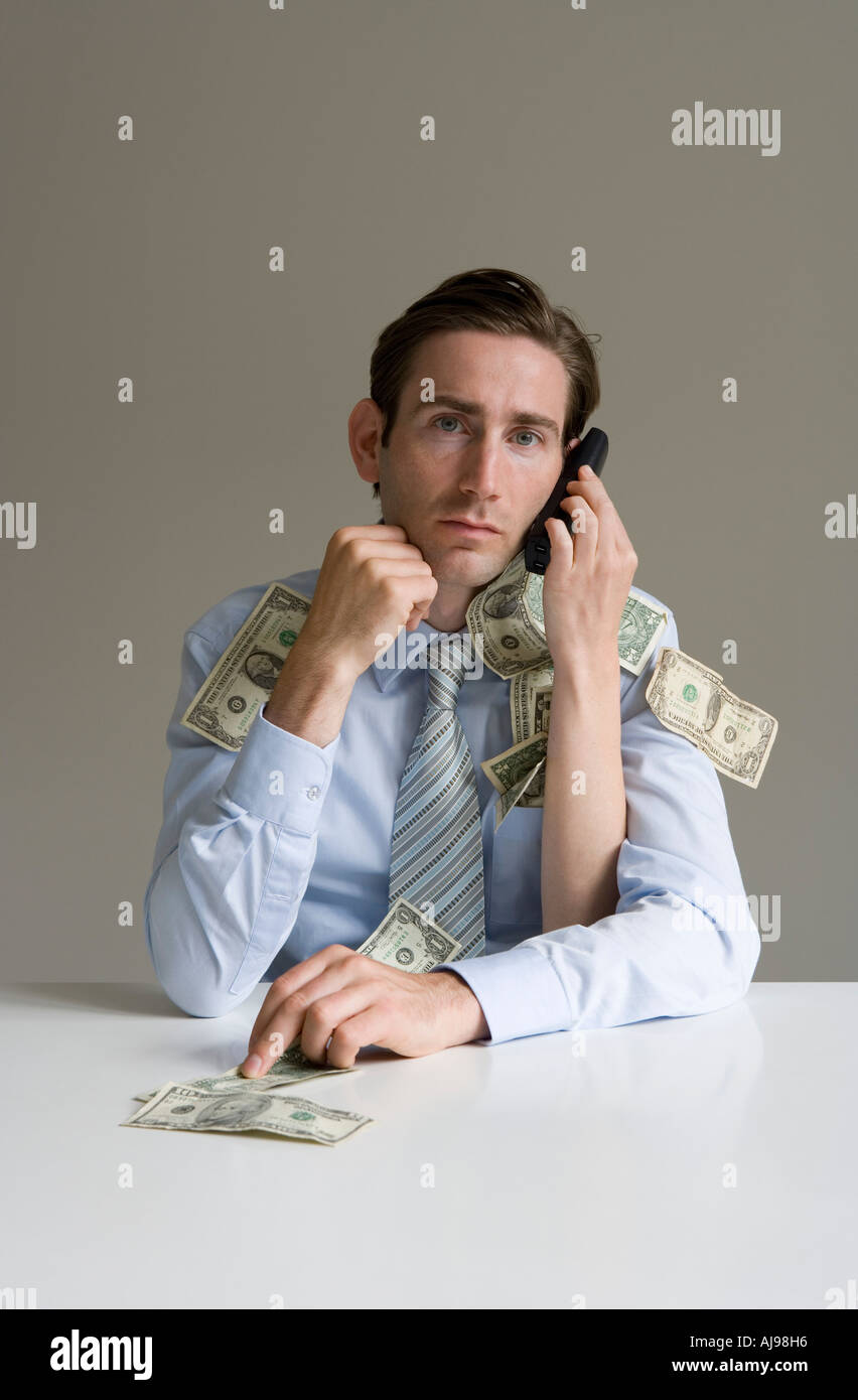 Businessman using telephone covered in money Stock Photo - Alamy
