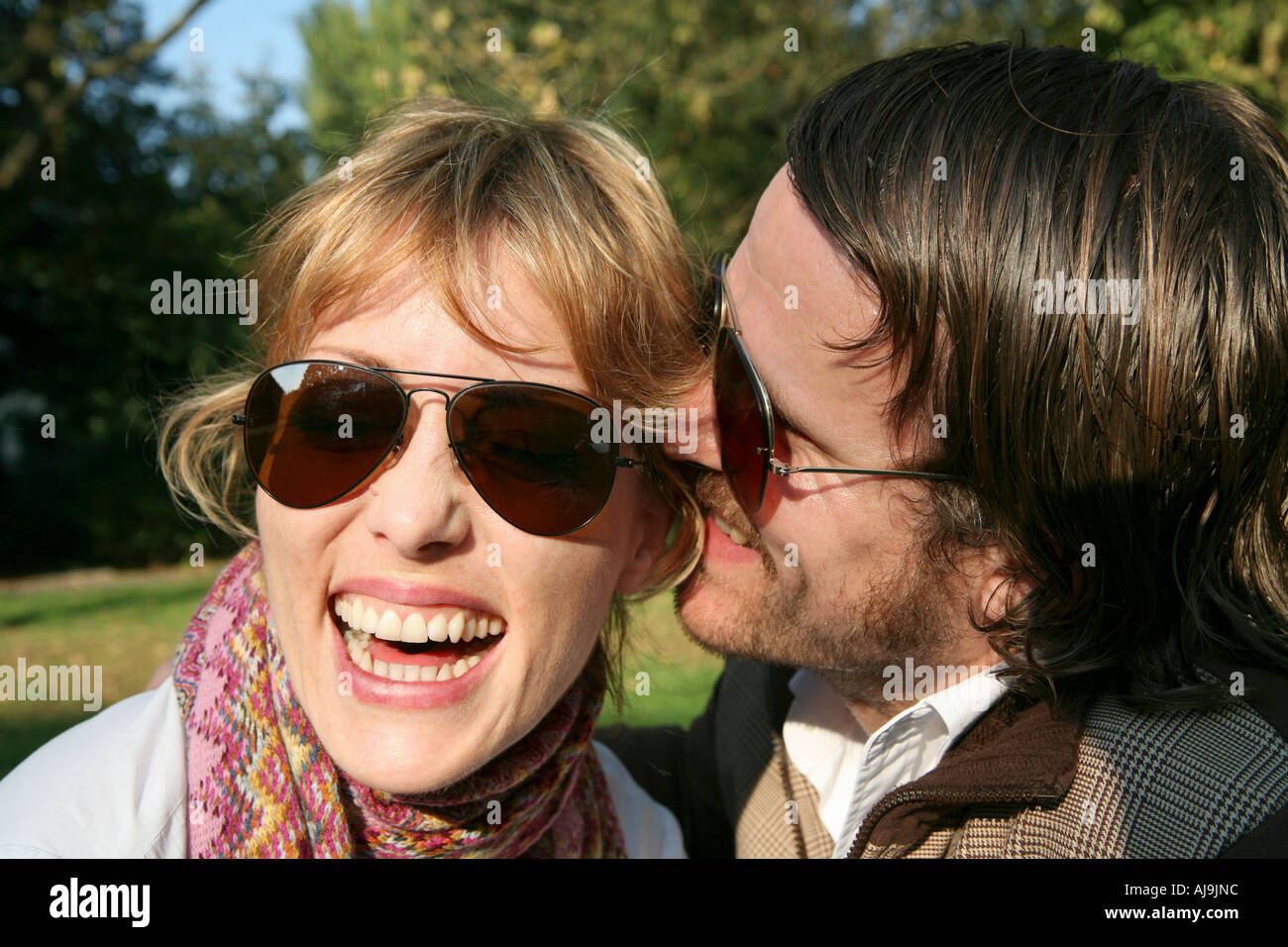 A man nuzzling a young woman s ear laughing Stock Photo - Alamy
