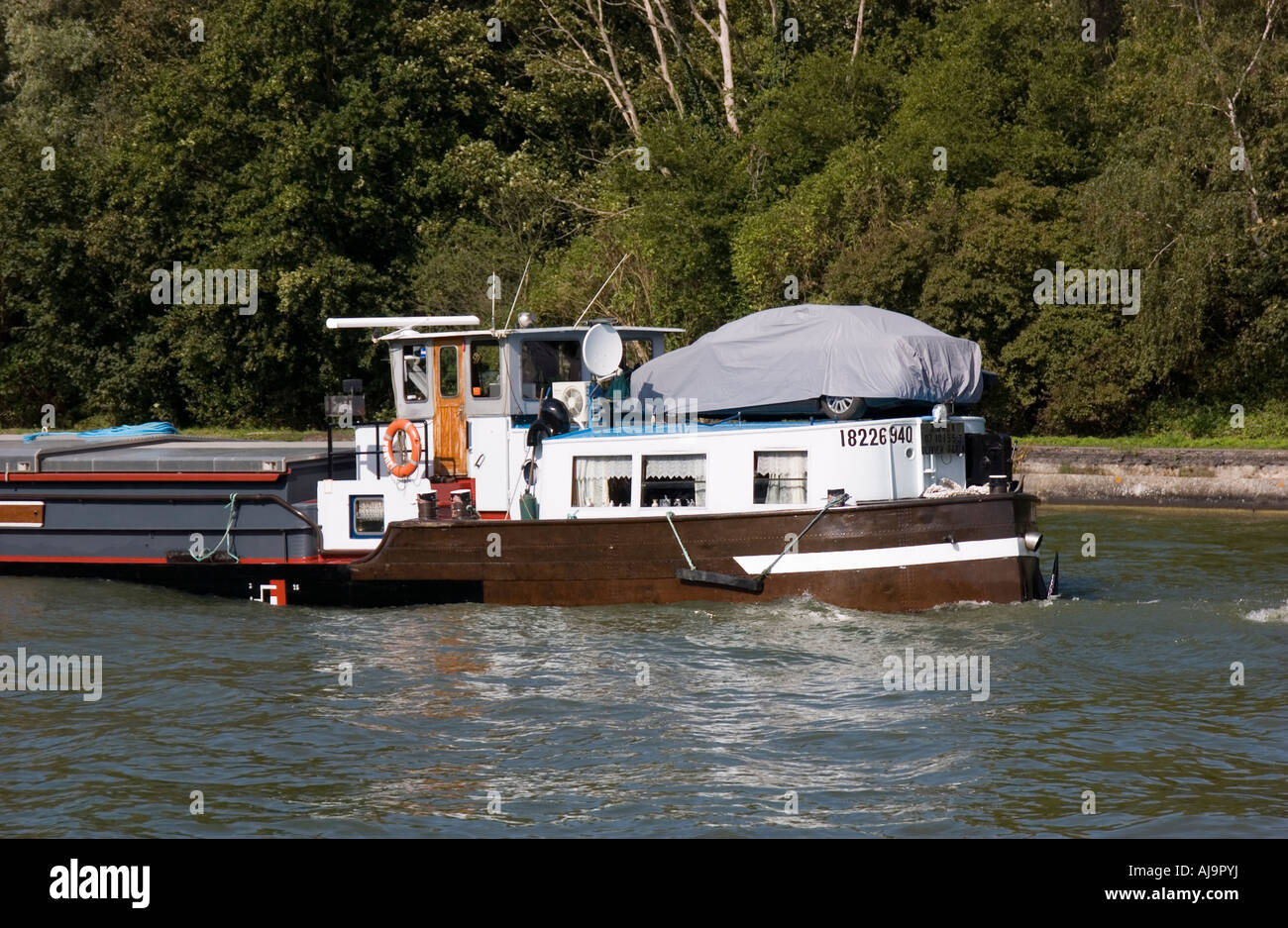 Commercial barge carrying a car under a tarpaulin on the aft deck on ...