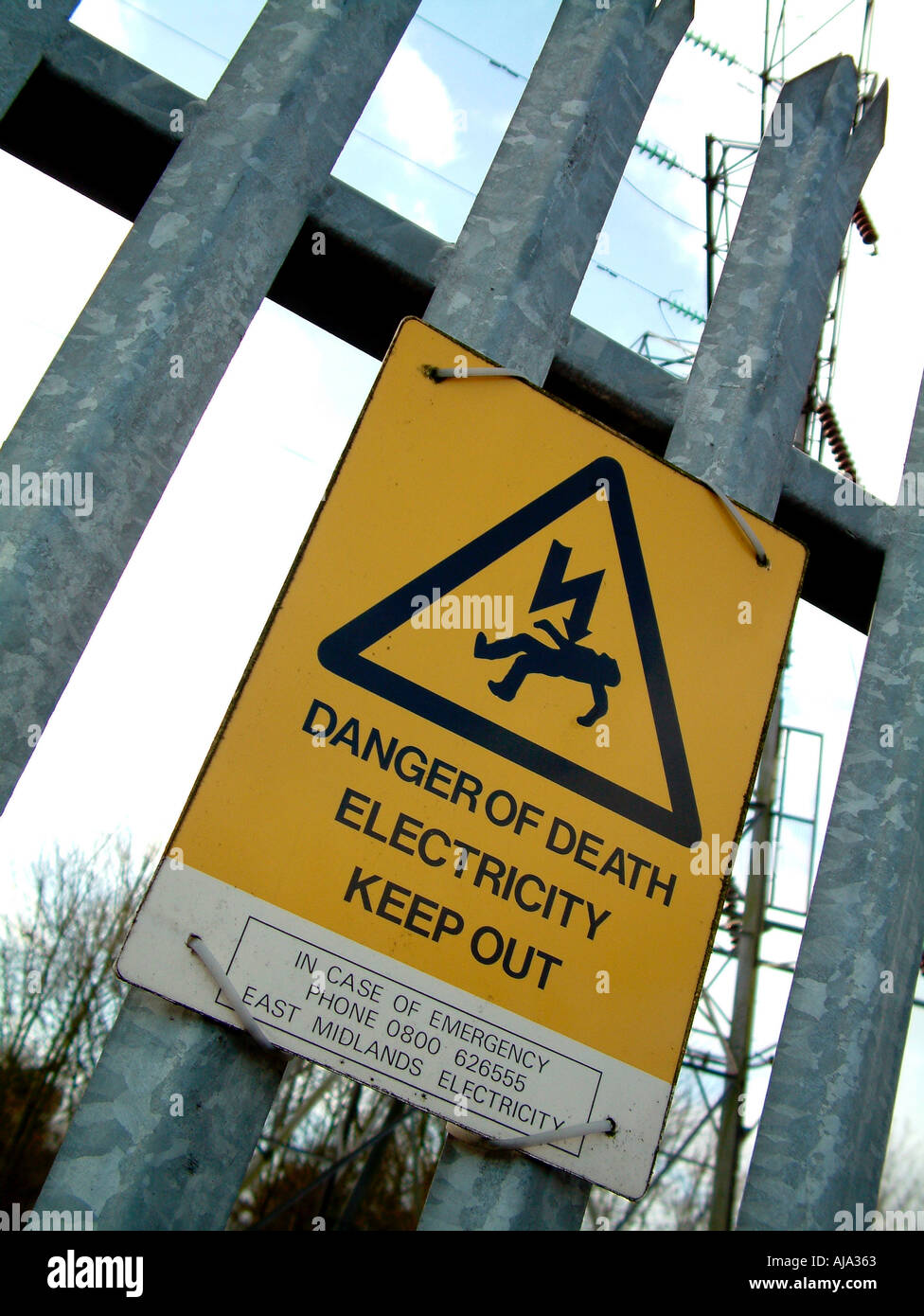 Danger High Voltage Sign on palisade fence with electricity pylon in ...