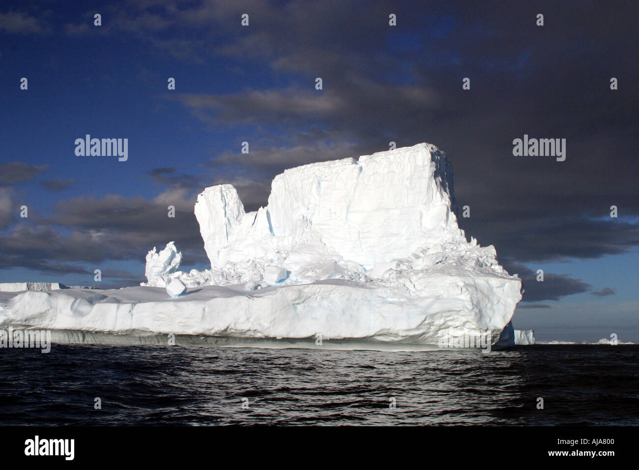 Flat iceberg with a dramatic black cloud in the background Stock Photo ...