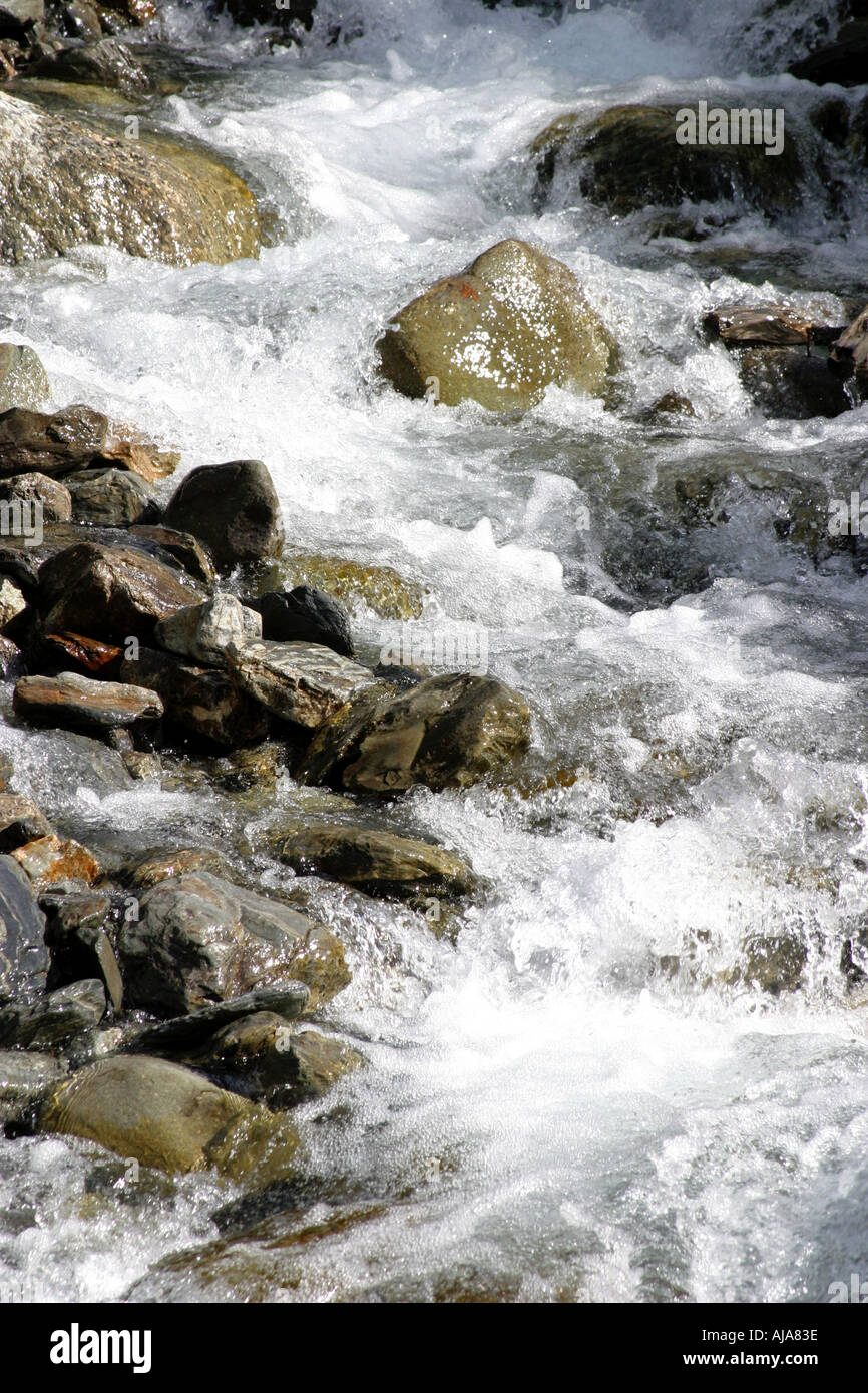 A bubbling brook running down the side of a mountain with rocks and ...