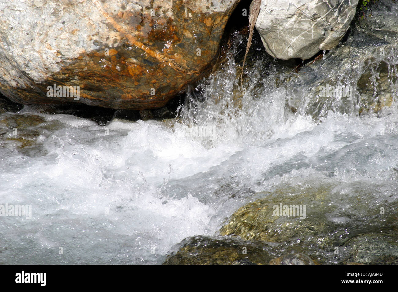 A bubbling brook running down the side of a mountain with rocks and ...