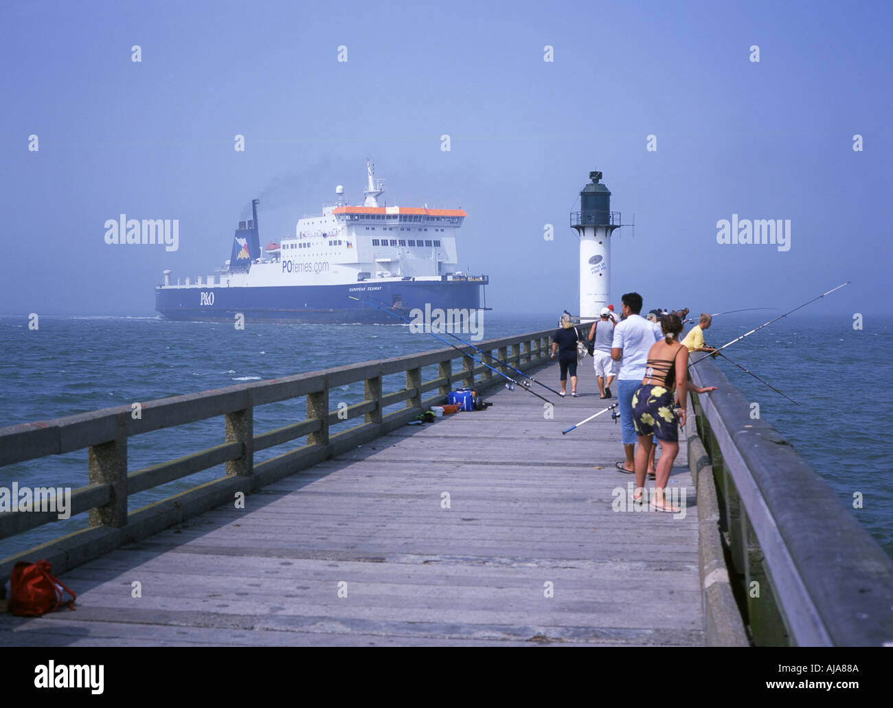 A cargo ferry sails into Calais harbour past the pier lighthouse and ...