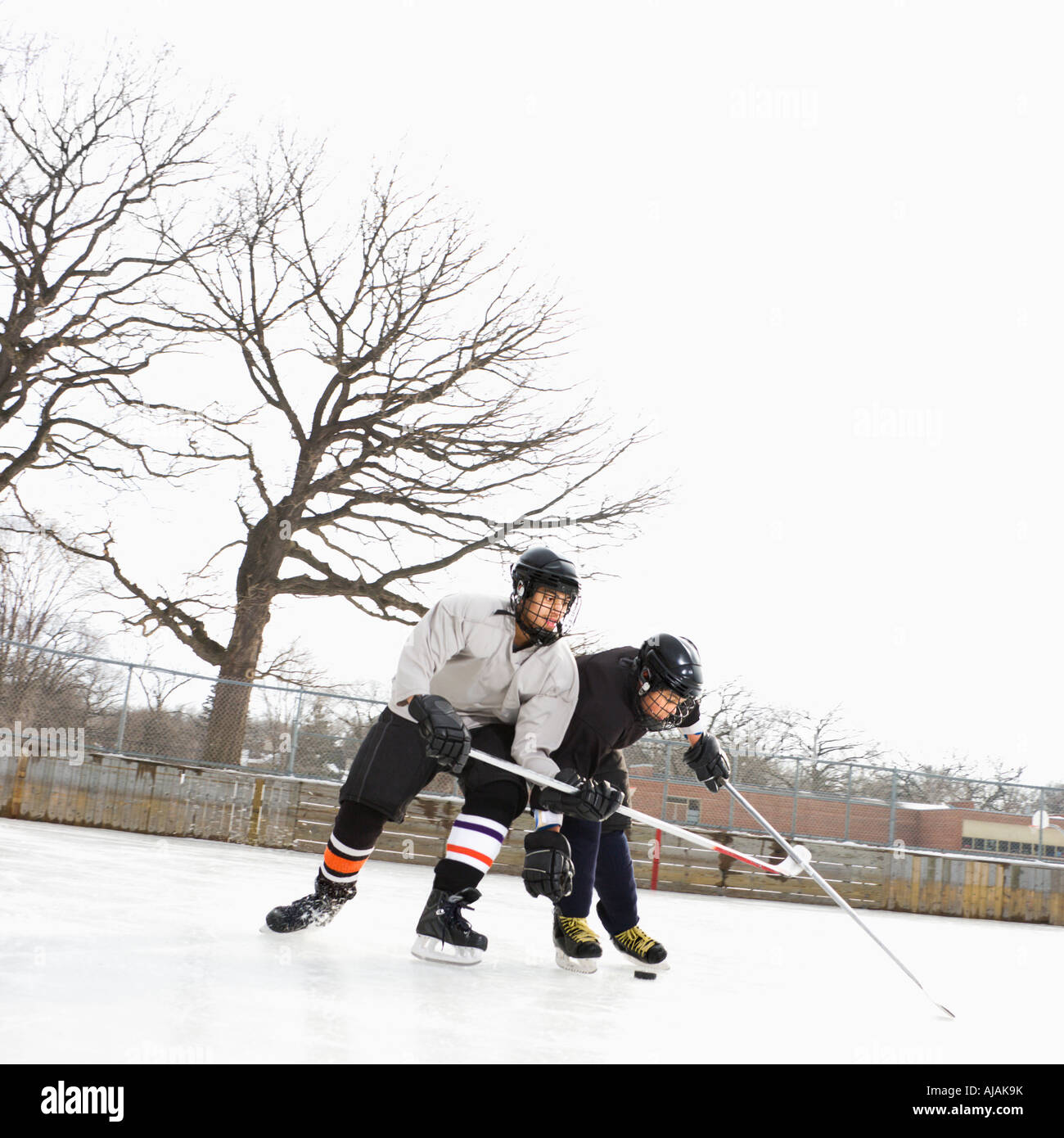 Two boys in ice hockey uniforms playing hockey on ice rink Stock Photo ...