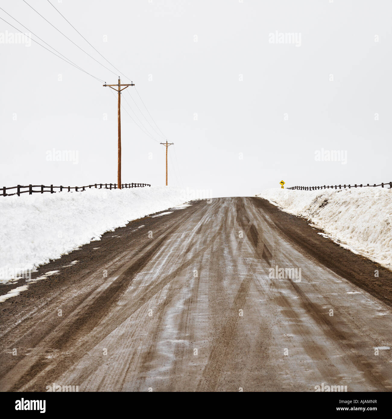 Muddy dirt road in rural snow covered landscape with power lines Stock ...