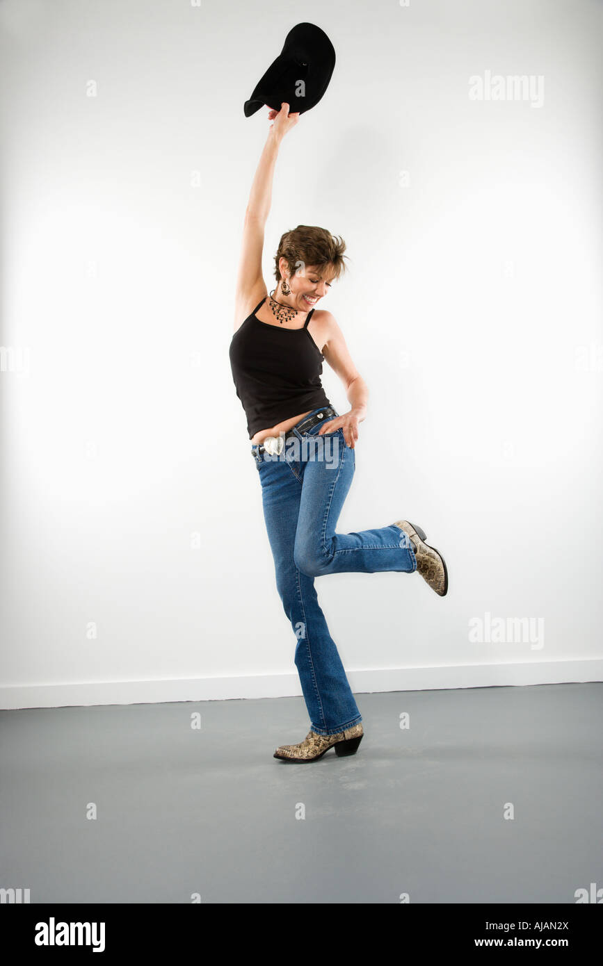 Full length portrait of pretty Caucasian woman holding up cowboy hat in ...