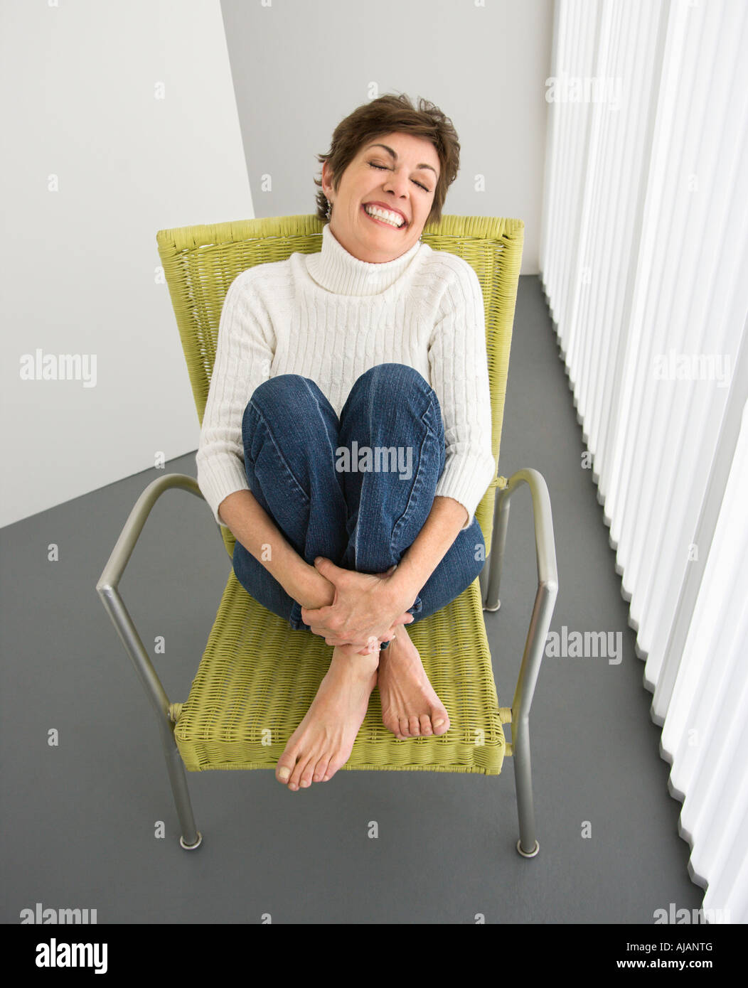 Portrait of pretty Caucasian woman smiling sitting on modern chair ...