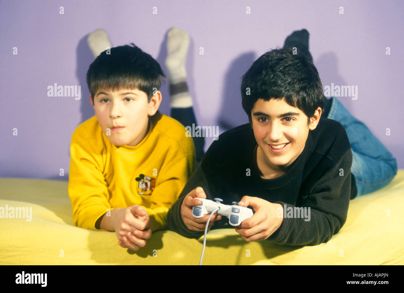 a young boy playing a computer game while his friend is watching Stock ...